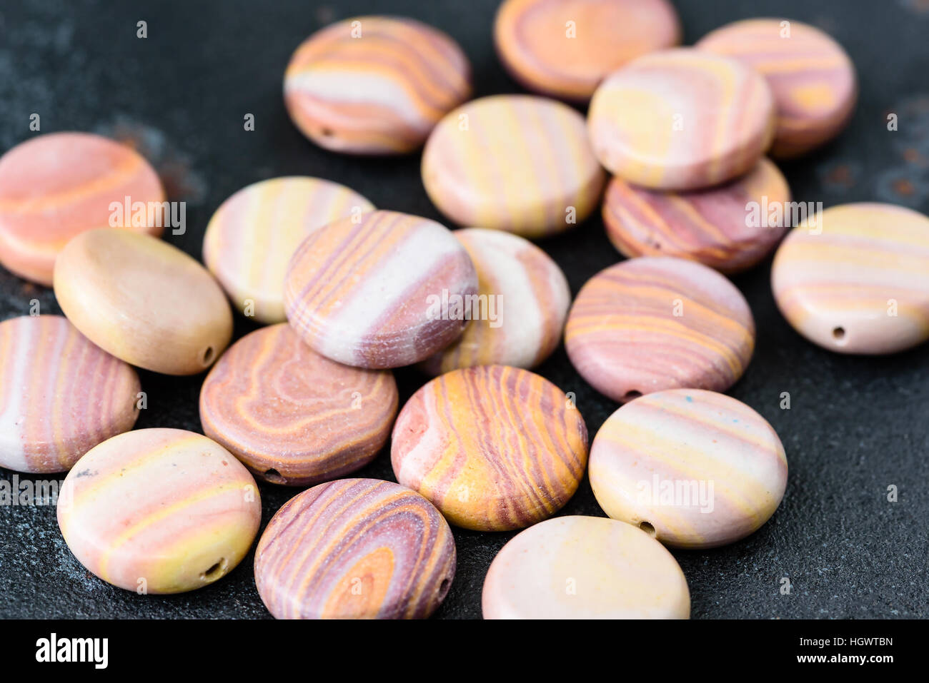 Collection of multicolored coin shaped hickoryite beads on black cast ...