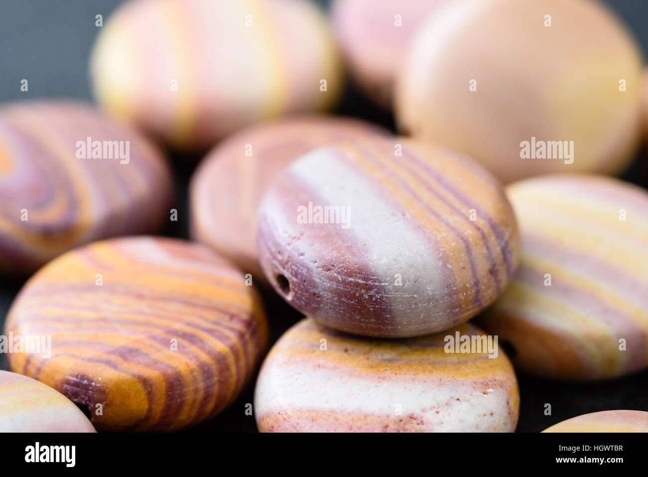 Collection of multicolored coin shaped hickoryite beads on black cast ...