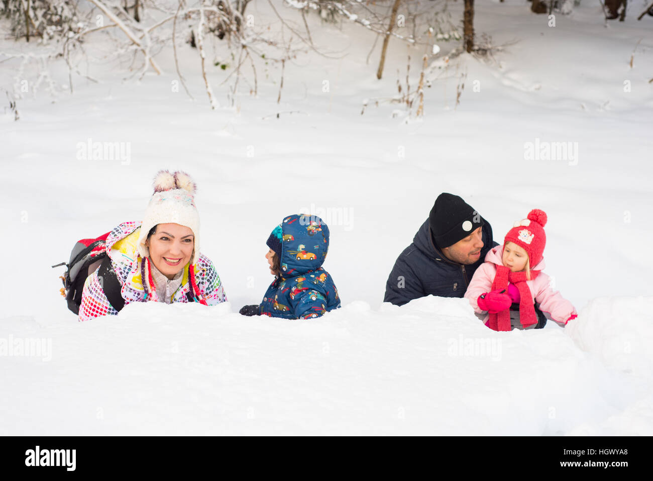 Happy family of four members lying down in snow in a row Stock Photo ...
