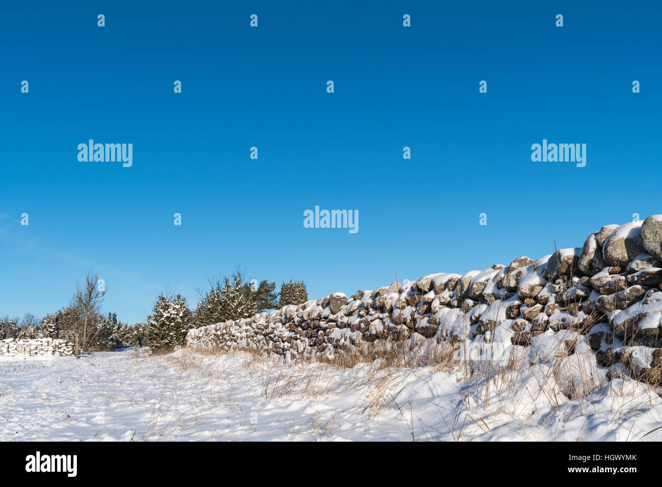 Winterland with a snow covered stone wall in a low perspective image ...