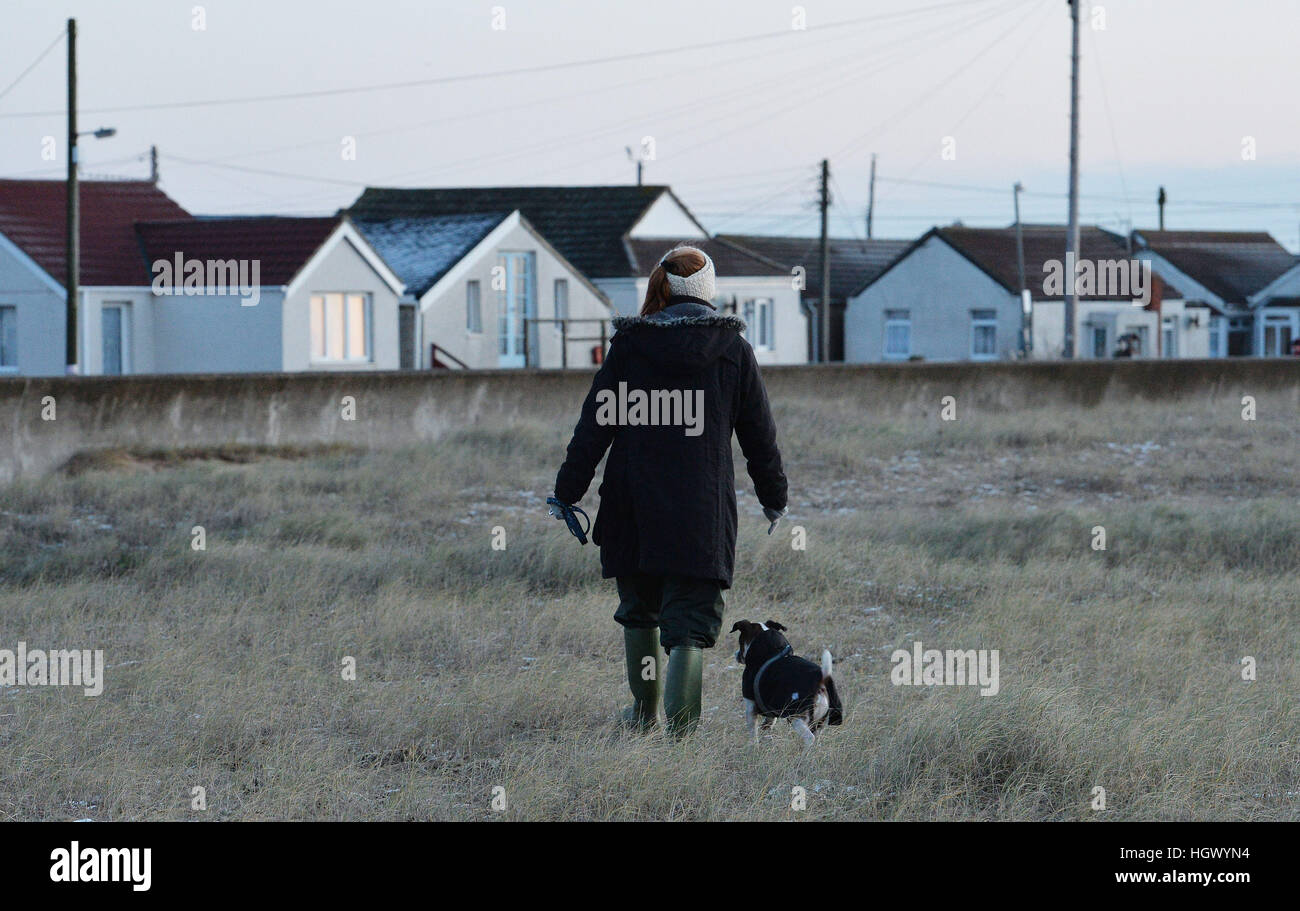 A resident walks her dog along the beach at Jaywick, Essex, from where ...
