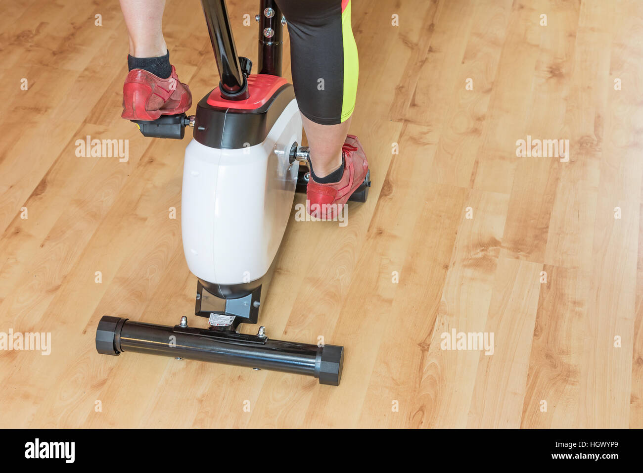 Back closeup view of the woman's legs training on the exercise bike ...