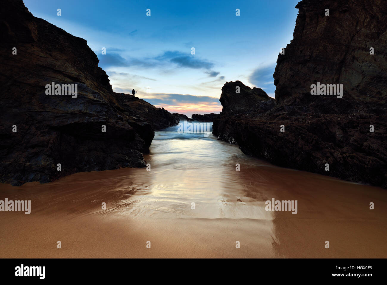 Rock cliffs surrounding natural beach with soft waves at sunset Stock ...