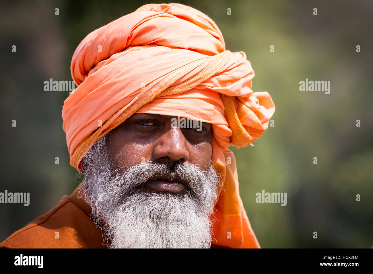 Head and shoulders portrait of a bearded Indian wearing an orange ...