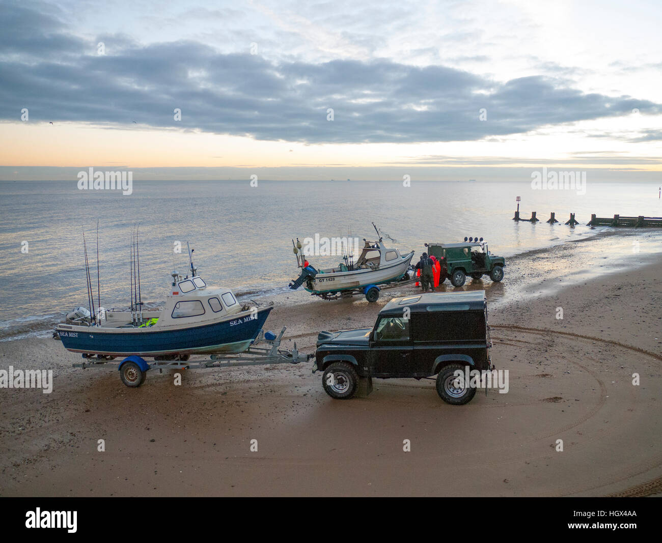 Launching small fishing boats, angling boats, off the sandy beach using ...