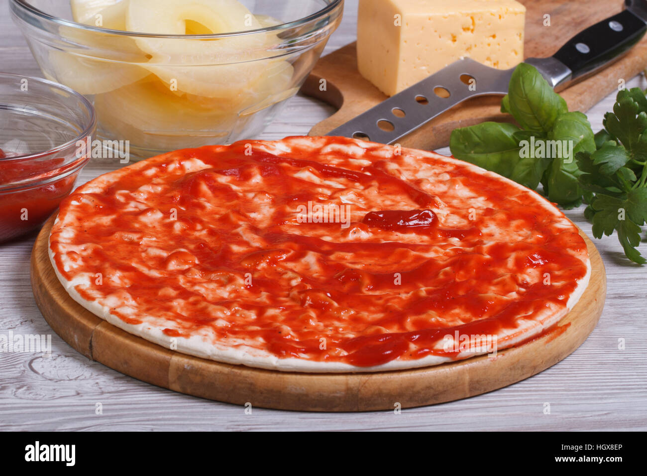 Pizza ingredients: base, tomato sauce, herbs, pineapple, cheese, close ...