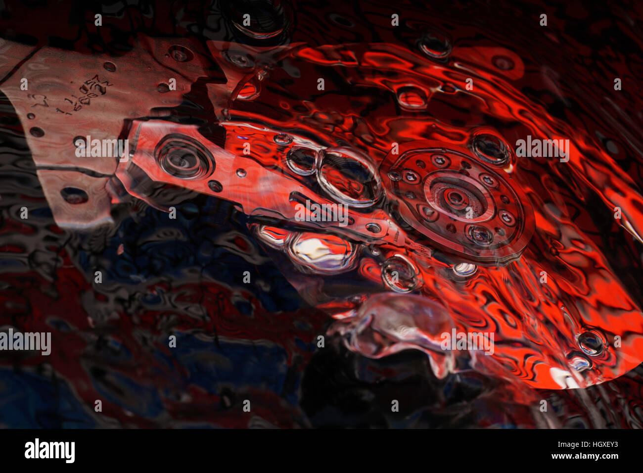 Opened Computer hard disk drive in studio with bubbles and dark red and ...