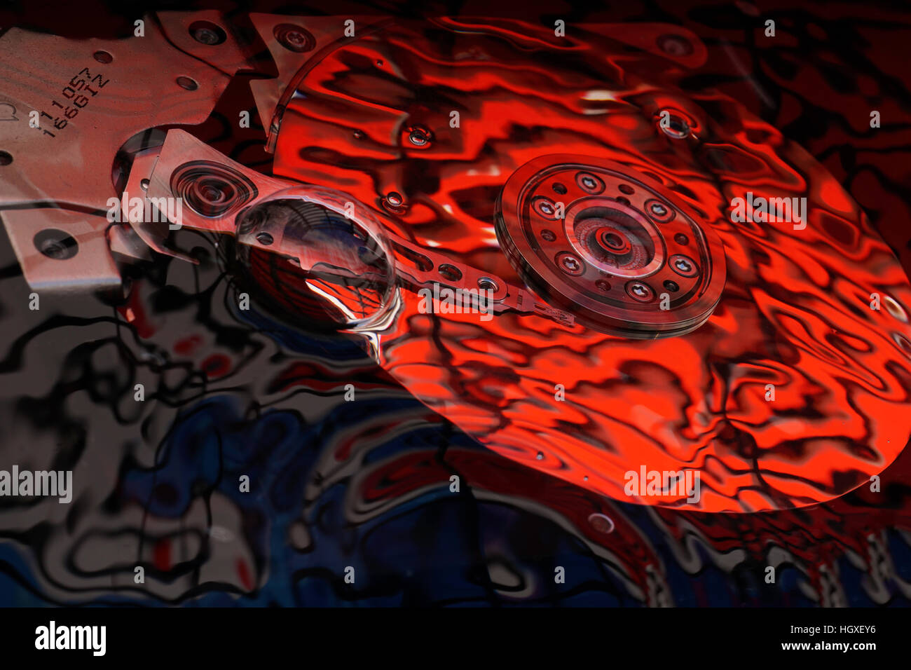 Opened Computer hard disk drive in studio with bubbles and dark red and ...