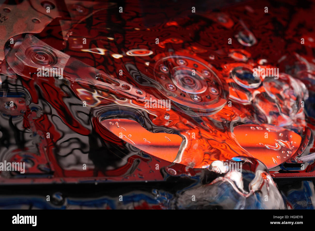 Opened Computer hard disk drive in studio with bubbles and dark red and ...