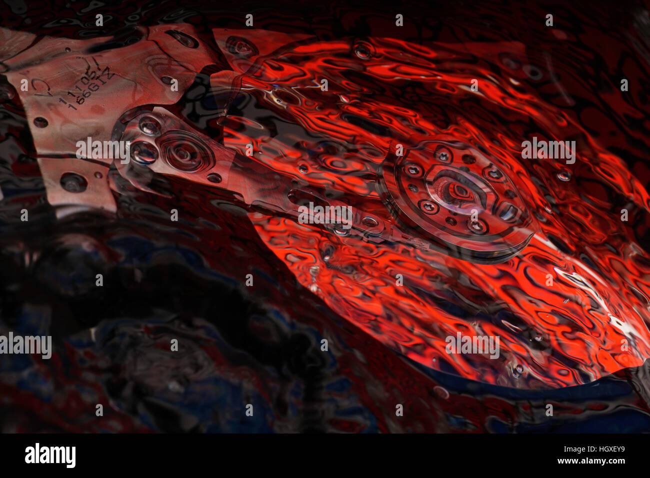 Opened Computer hard disk drive in studio with bubbles and dark red and ...