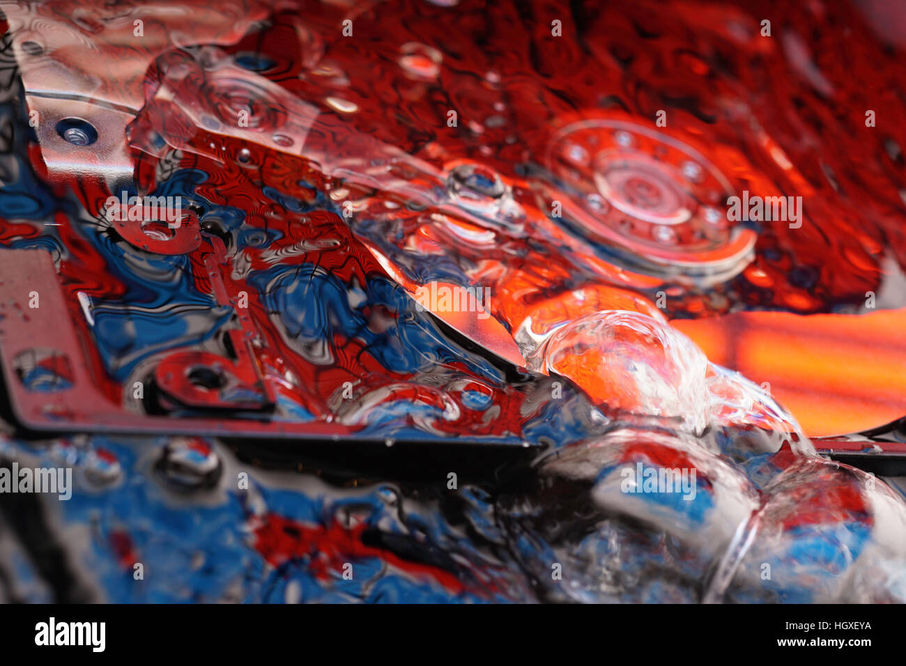 Opened Computer hard disk drive in studio with bubbles and dark red and ...
