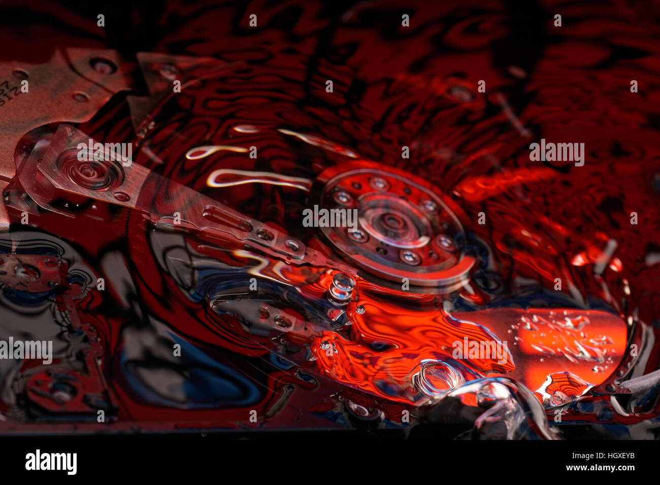 Opened Computer hard disk drive in studio with bubbles and dark red and ...
