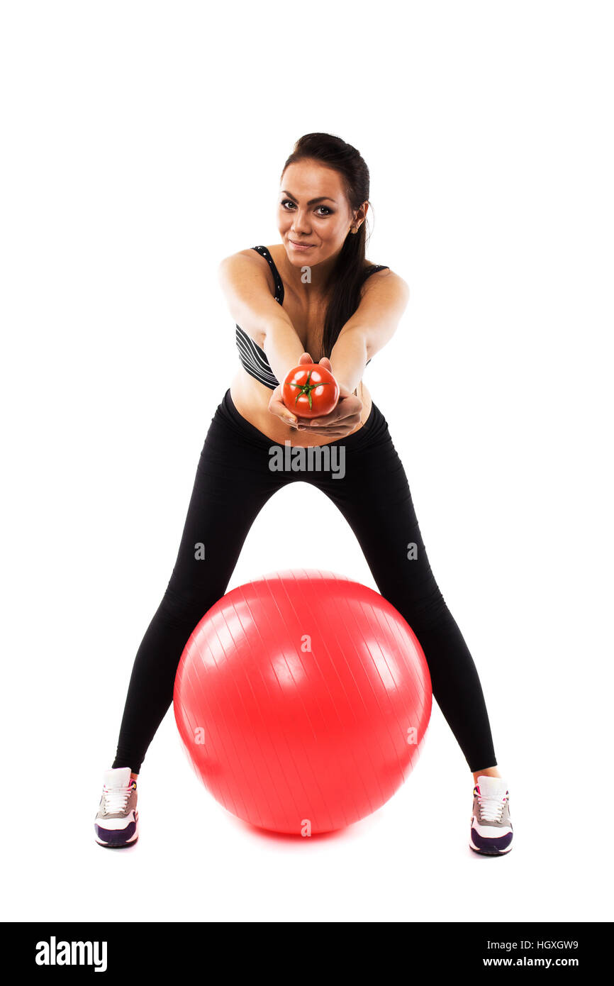 Slim girl wearing sport clothing standing near red gym ball offering a ...