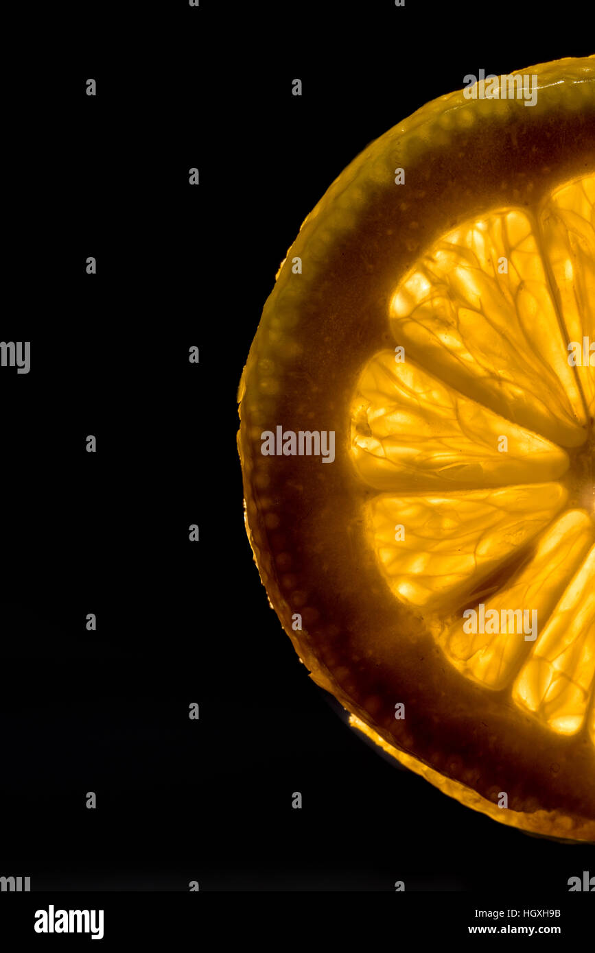 Half a slice of lemon, back lit with black background Stock Photo - Alamy