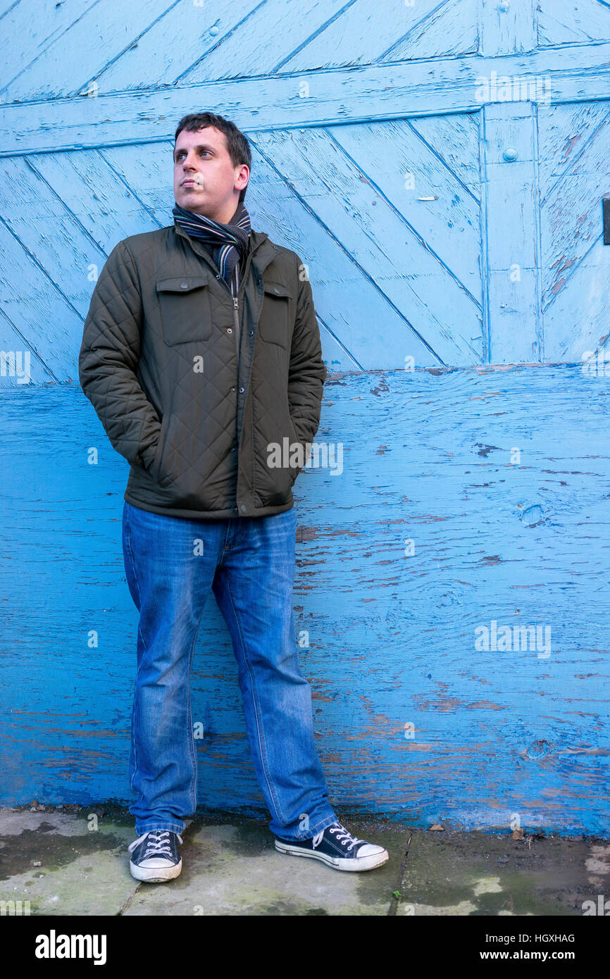Man stood in front of blue wooden door Stock Photo - Alamy