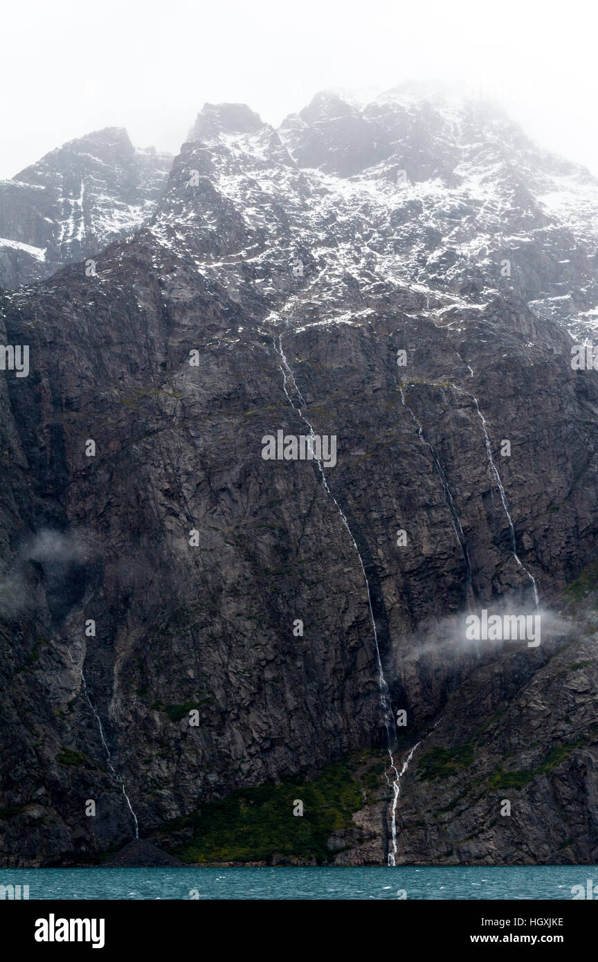 Waterfalls cascade down sheer cliffs into the ocean from melting ...