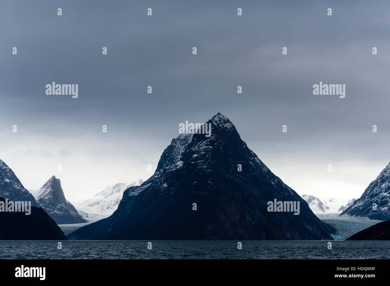 A cone-shaped mountain rises from the dark waters of an Arctic fjord ...