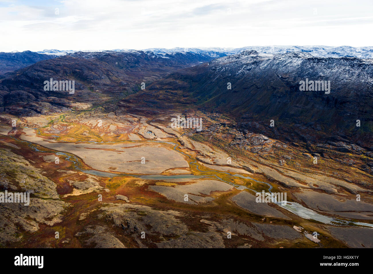 A winding river snakes it's way across a highland tundra valley floor ...