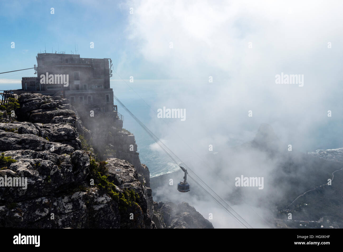 A cable car rises to the summit of Table Mountain through a cloud bank ...