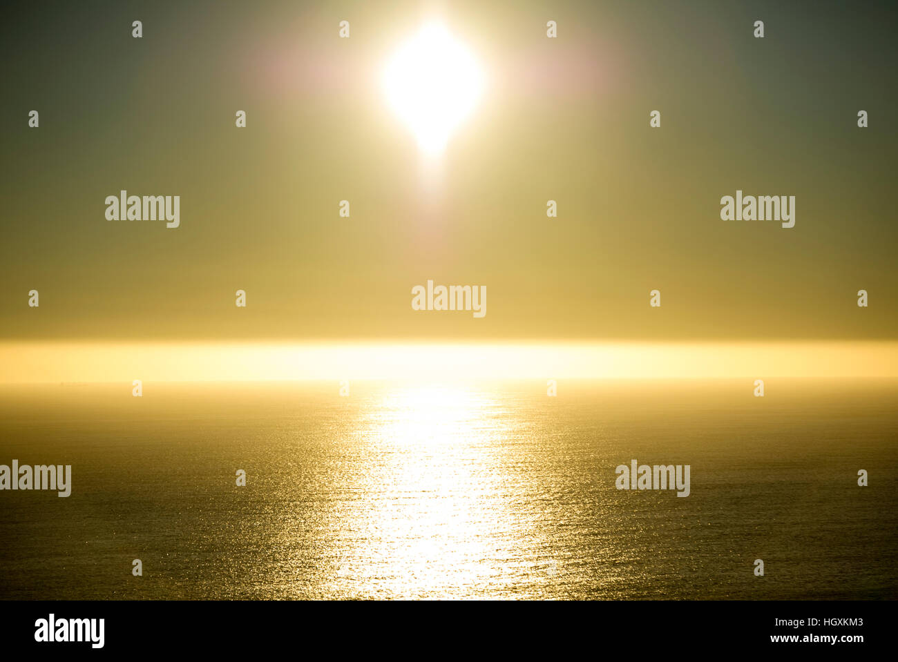 The sun casts a golden pillar on the ocean as it dips toward sunset ...