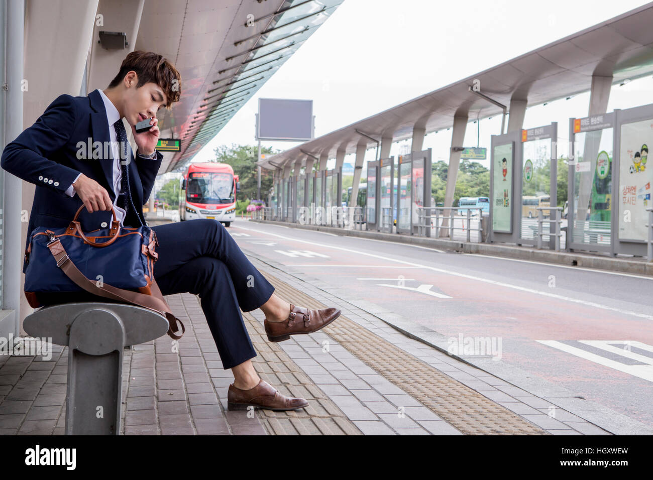 Businessman talking on cellphone at bus stop Stock Photo - Alamy