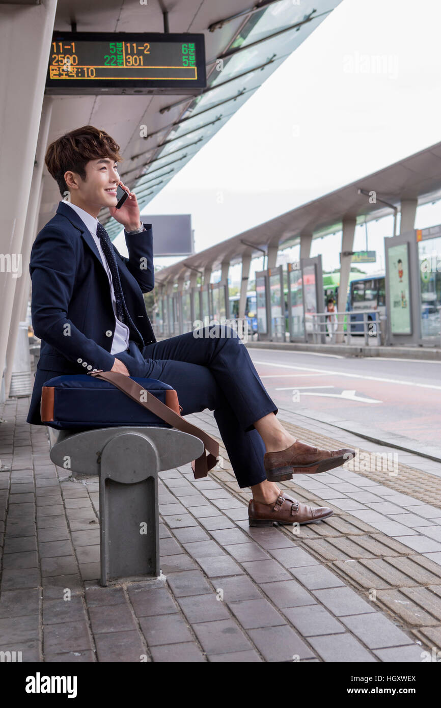 Businessman talking on cellphone at bus stop Stock Photo - Alamy