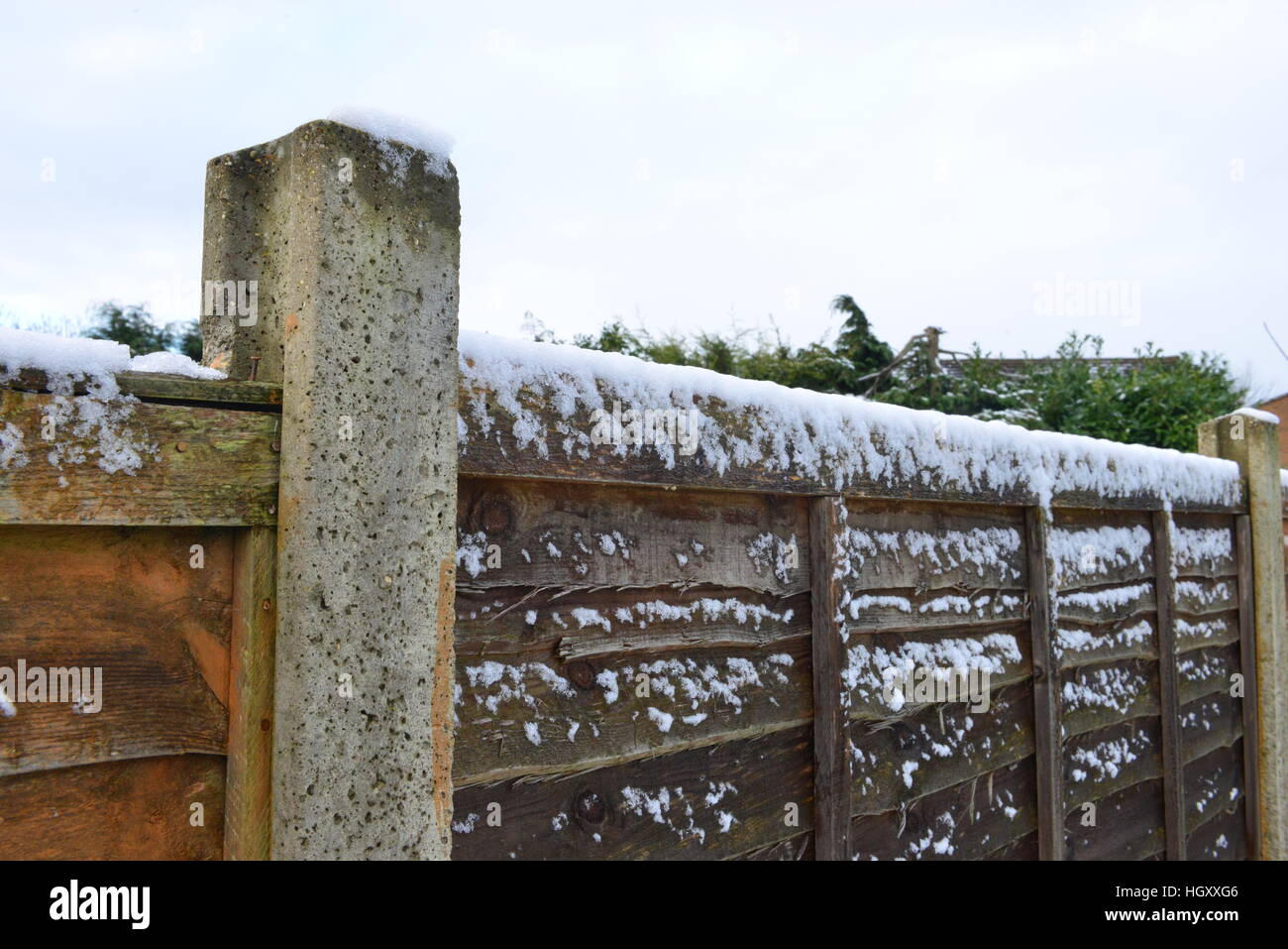 A frozen concrete post and a snow covered fence in the England in ...