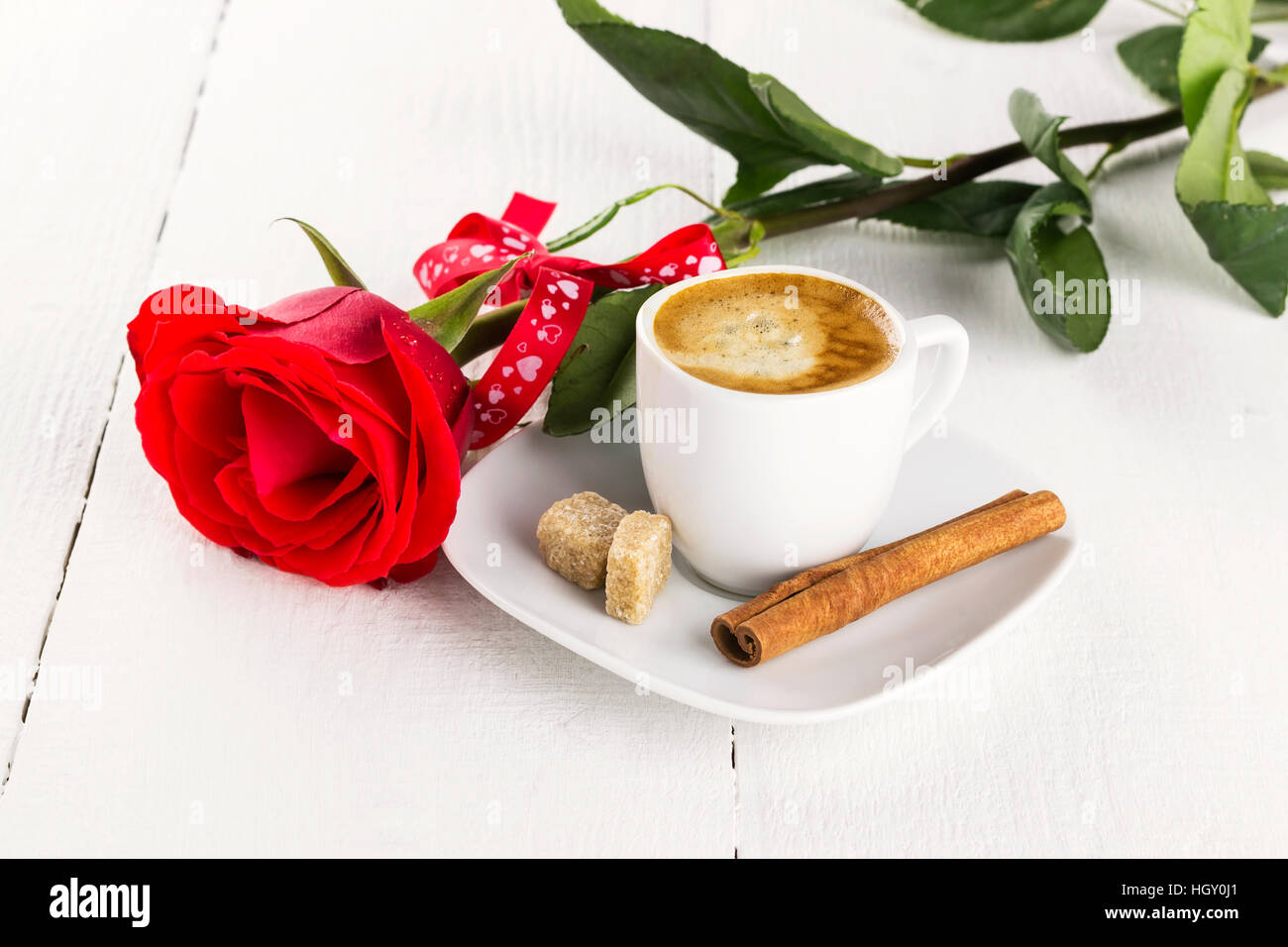 Cup of coffee, red rose, sugar and cinnamon on a white wooden ...