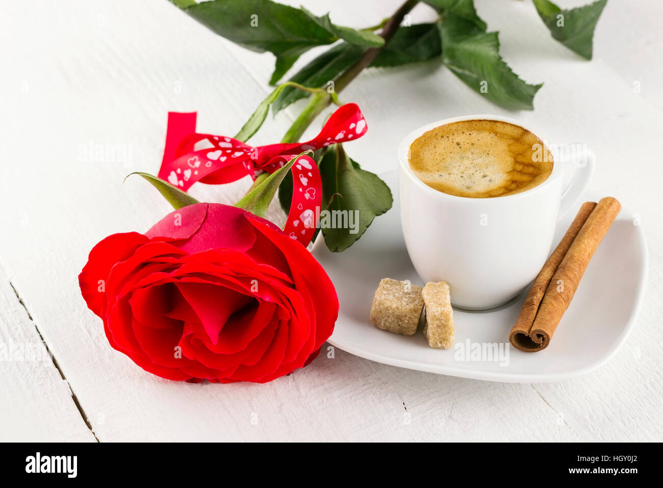 Cup of coffee, red rose, sugar and cinnamon on a white wooden ...