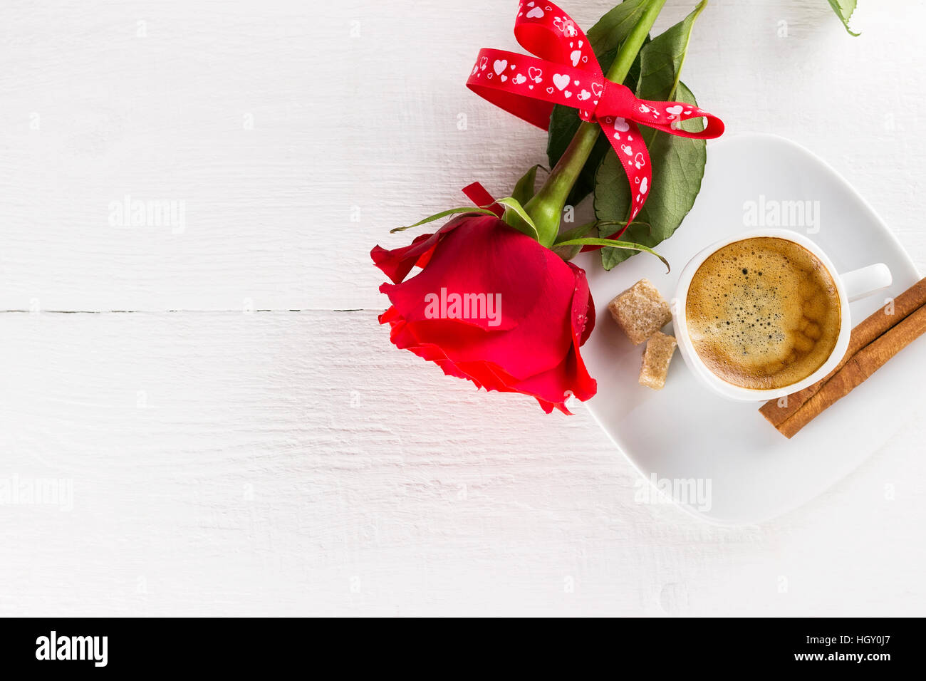 Cup of coffee, red rose, sugar and cinnamon on a white wooden ...