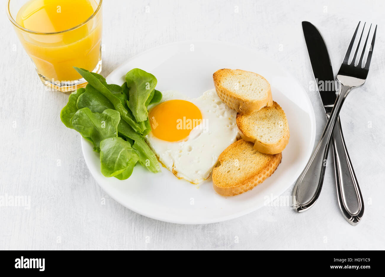 Breakfast: fried eggs with greens, orange juice on a white background ...