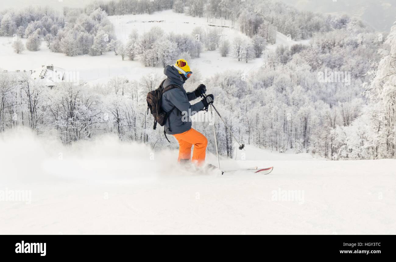 Skier skiing on ski slope with winter mountain in background Stock ...