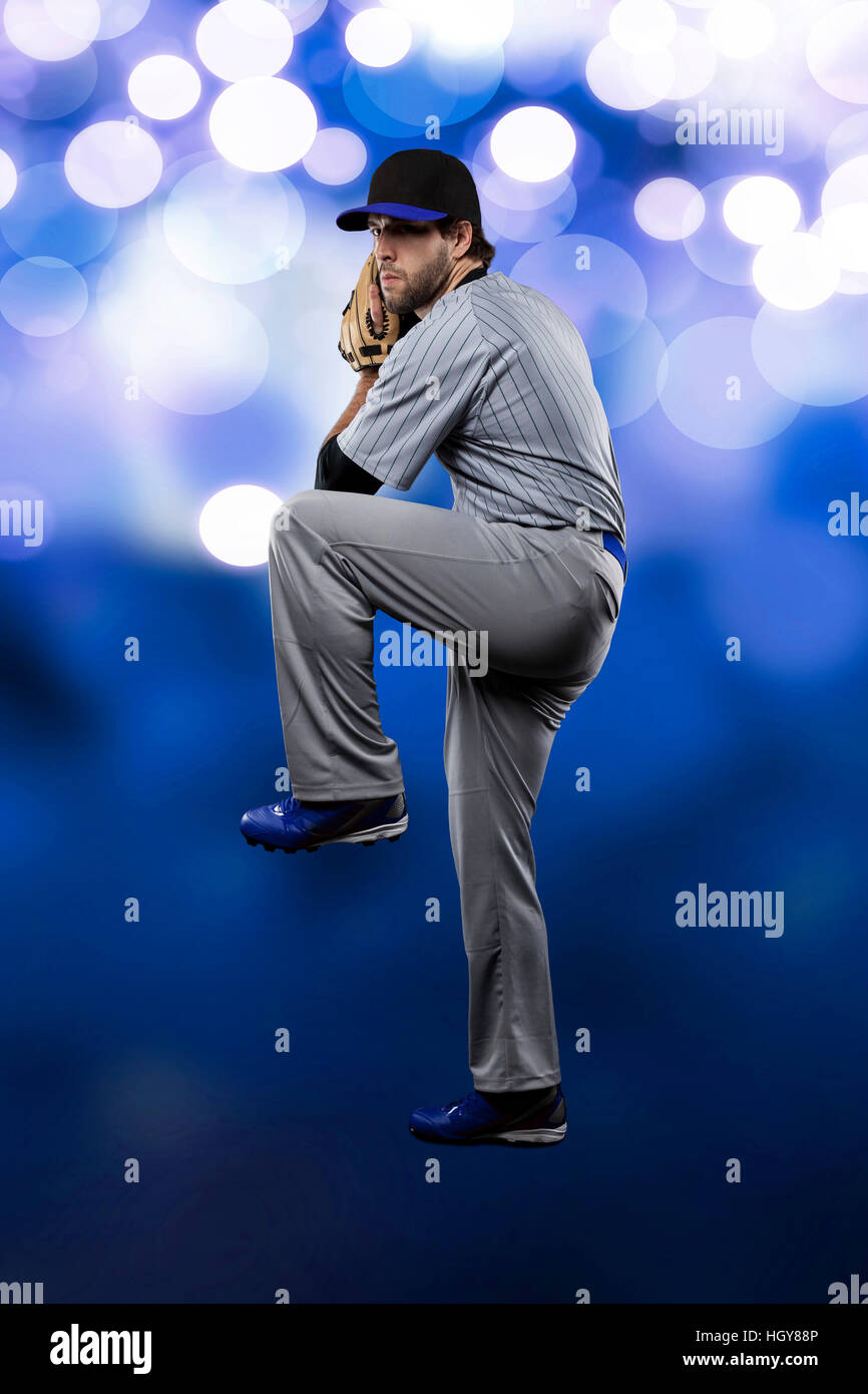 Pitcher Baseball Player on a blue Uniform on blue lights background ...