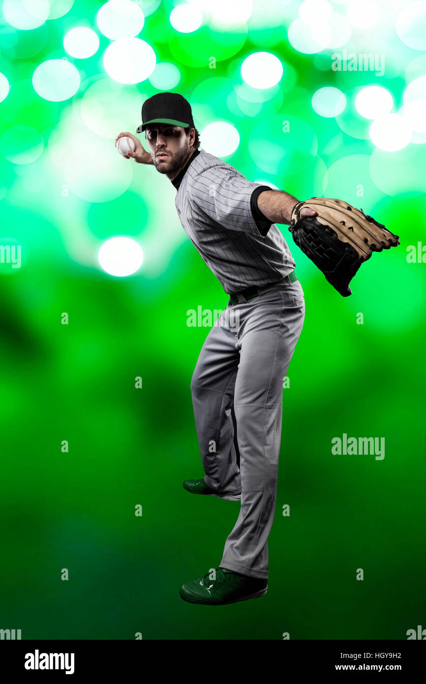 Pitcher Baseball Player on a Green Uniform on Green lights background ...