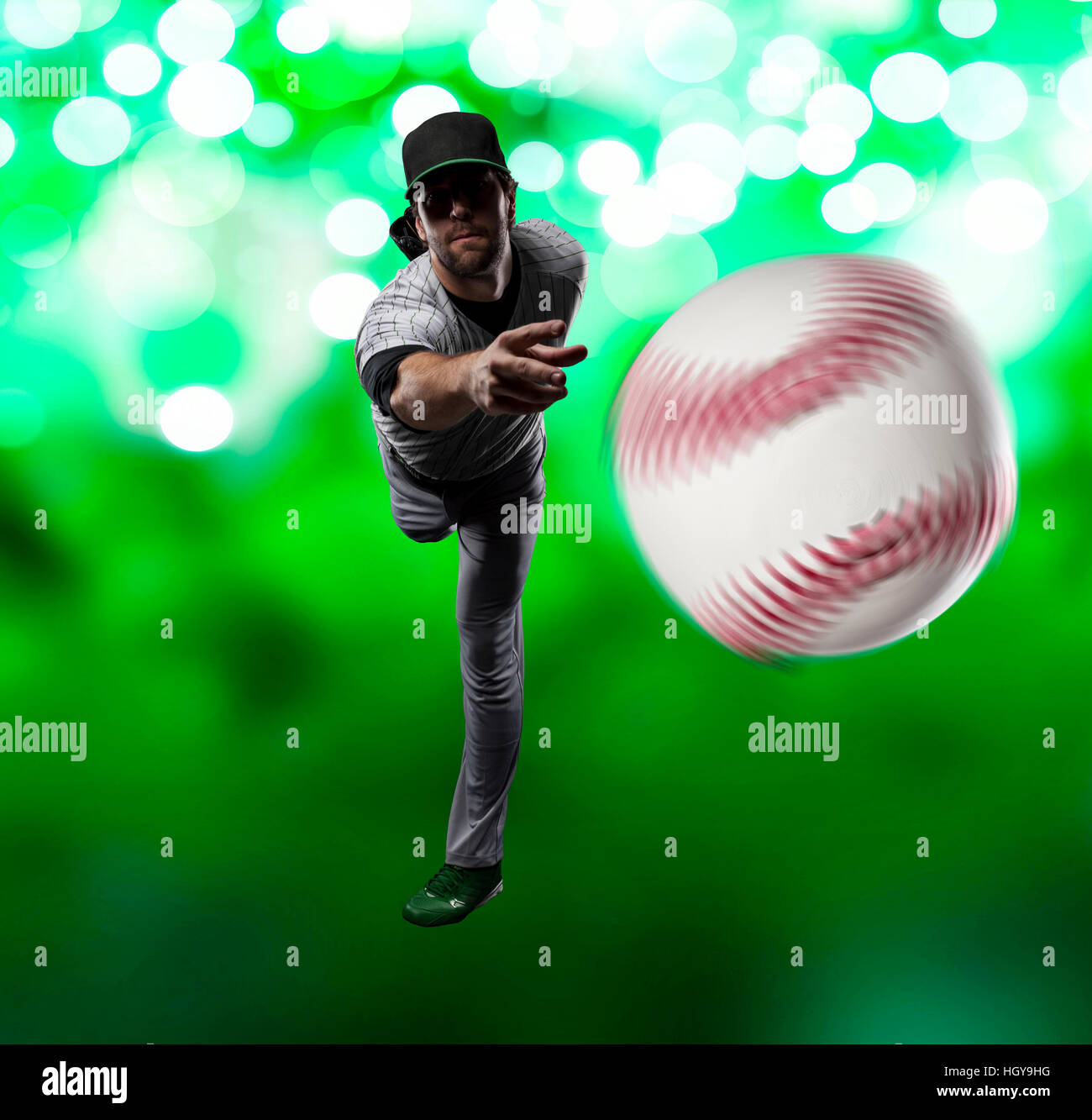 Pitcher Baseball Player on a Green Uniform on Green lights background ...