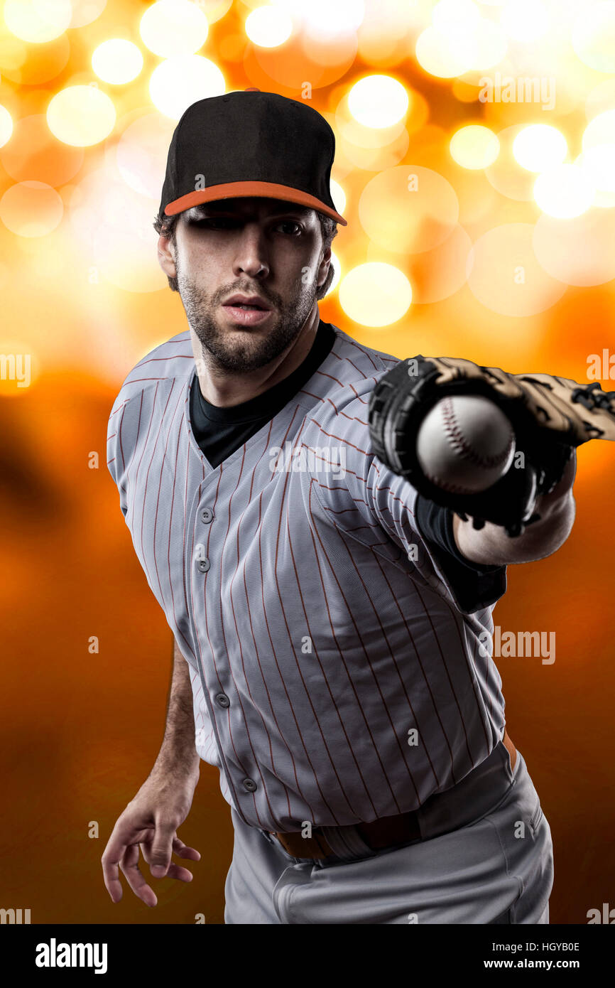 Baseball Player on a orange Uniform on orange lights background Stock ...