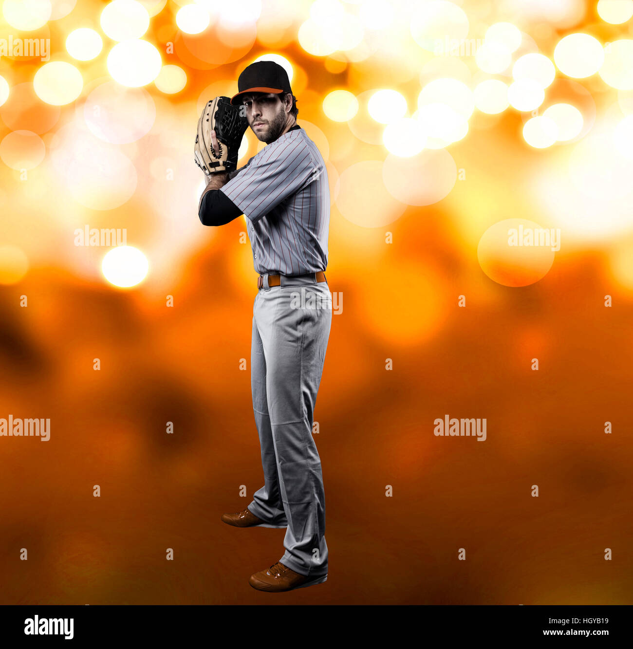 Pitcher Baseball Player on a orange Uniform on orange lights background ...