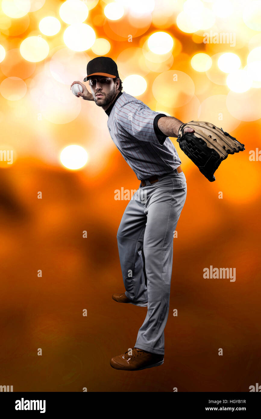 Pitcher Baseball Player on a orange Uniform on orange lights background ...