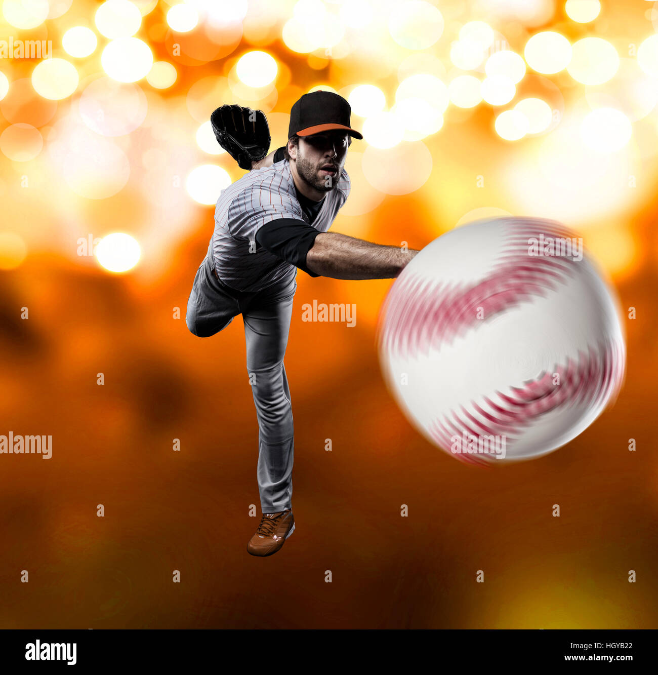Pitcher Baseball Player on a orange Uniform on orange lights background ...