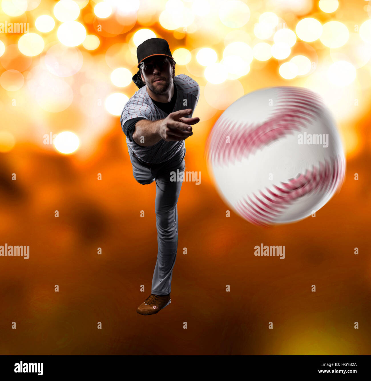 Pitcher Baseball Player on a orange Uniform on orange lights background ...