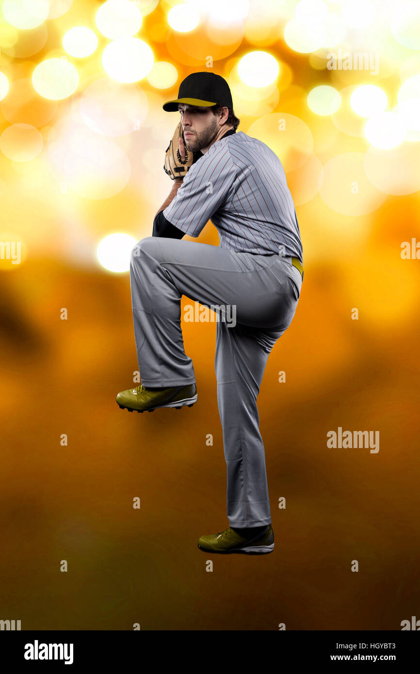 Pitcher Baseball Player on a yellow Uniform on yellow lights background ...