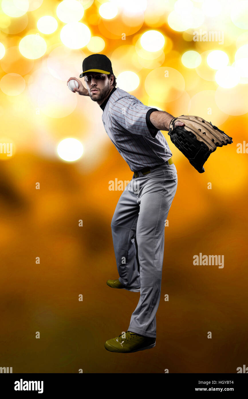 Pitcher Baseball Player on a yellow Uniform on yellow lights background ...