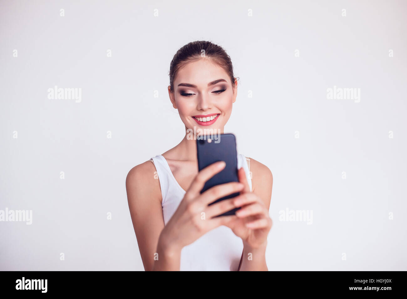 Beautiful brunette girl with makeup make selfie on white background ...
