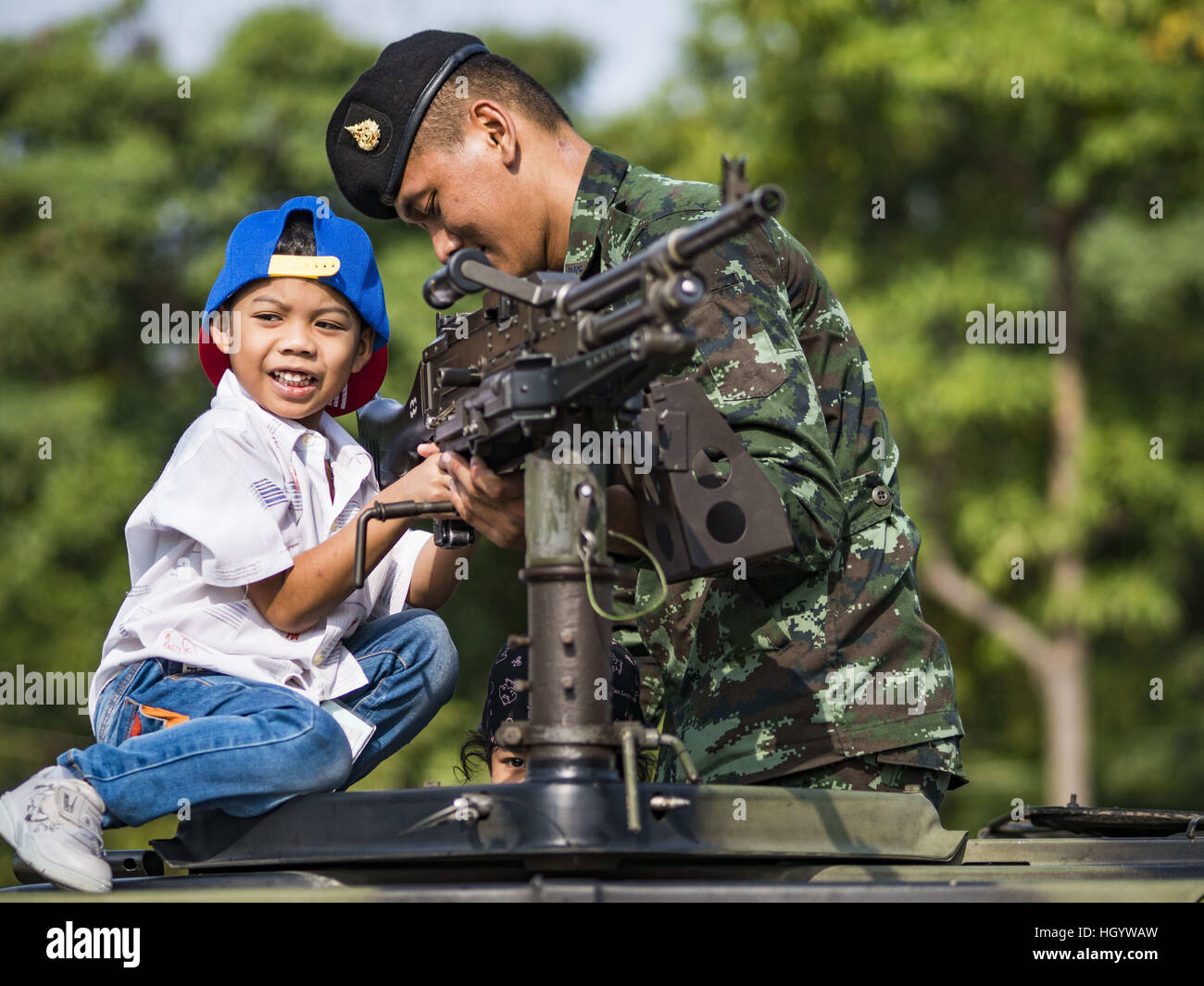 Bangkok, Thailand. 14th Jan, 2017. A Thai soldier helps a child look at ...