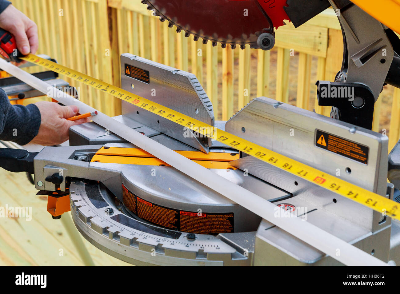 Carpenter cutting wooden plank with circular saw wearing safety ...