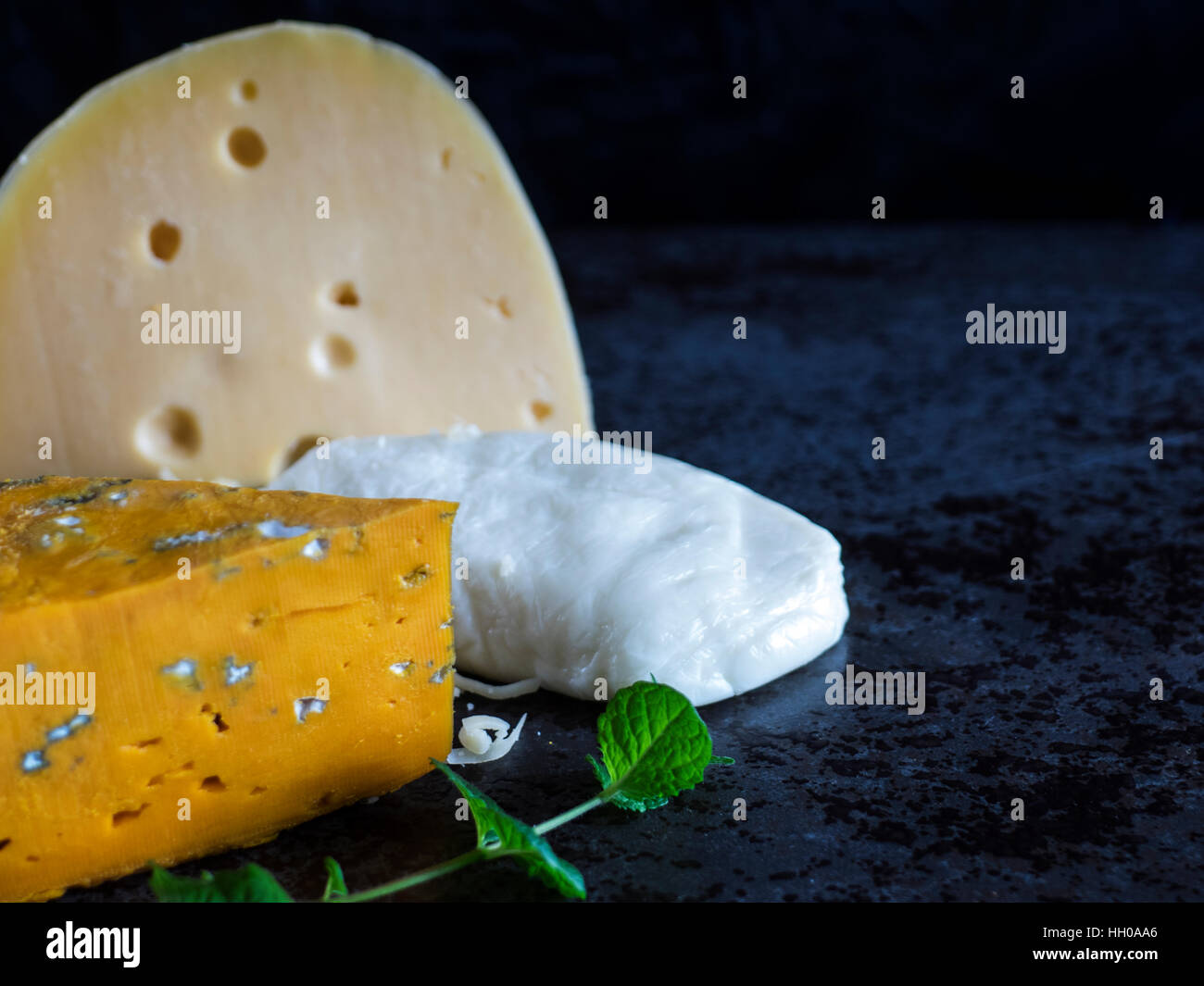 Fresh pieces of cheese (Mozzarella, roquefort, Maasdam) on the stone ...