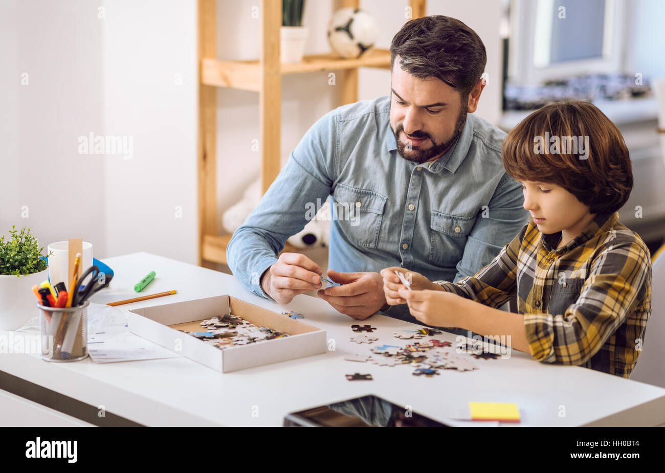 Serious father and son making picture of puzzles Stock Photo - Alamy