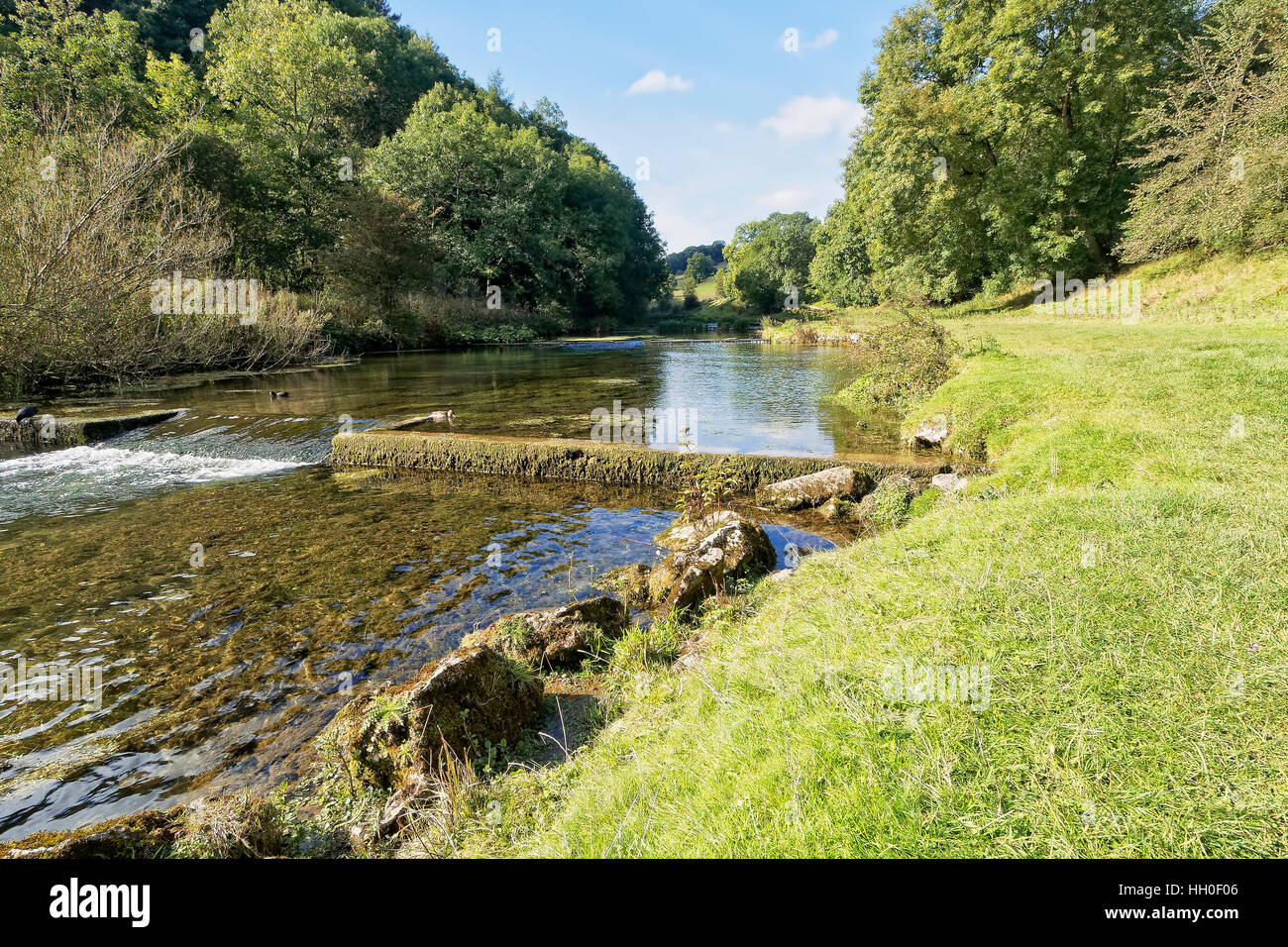 On a bright sunny autumn day the shallow, clear River Lathkill flows ...