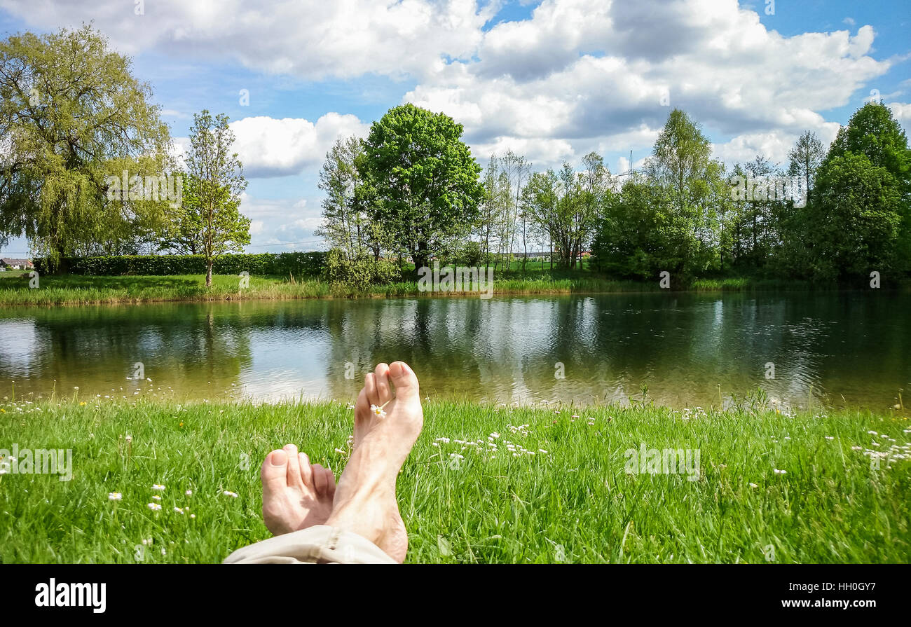 Legs and feet relaxing in front of serene fresh water pond Stock Photo ...