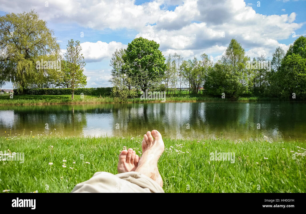 Legs and feet relaxing in front of serene fresh water pond Stock Photo ...